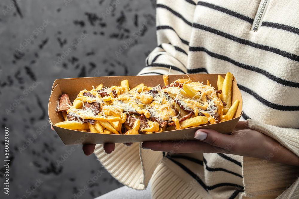 Close up of traditional Fries with cheese and bacon in a paper plate at ...