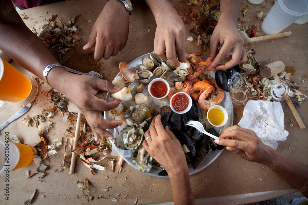 Tourists dig into a seafood feast. Stock Photo | Adobe Stock