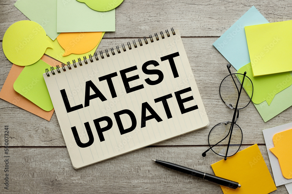 Flat lay, top view office table desk. LATEST UPDATE text on a notepad ...