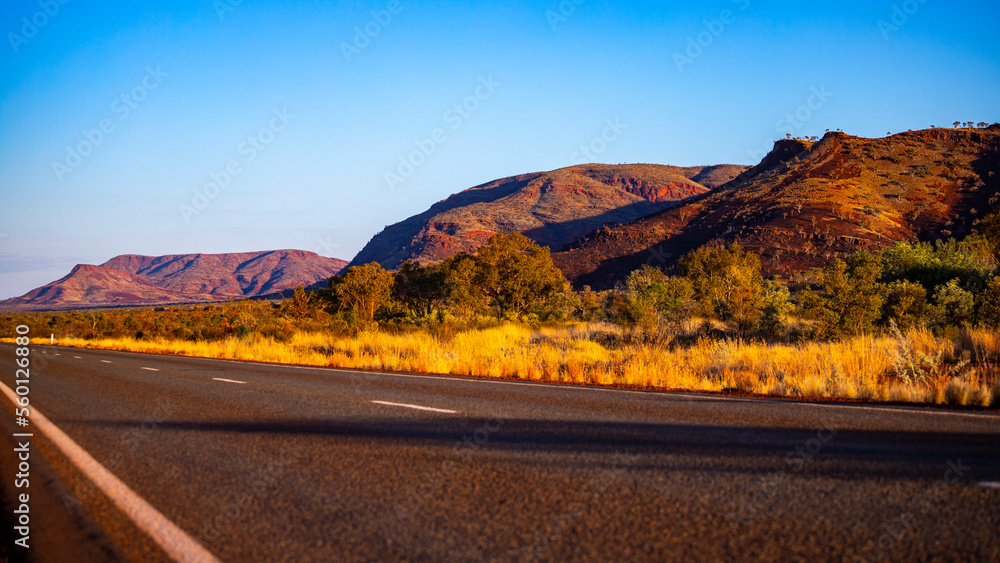 sunrise in karijini national park in western australia; a road through ...