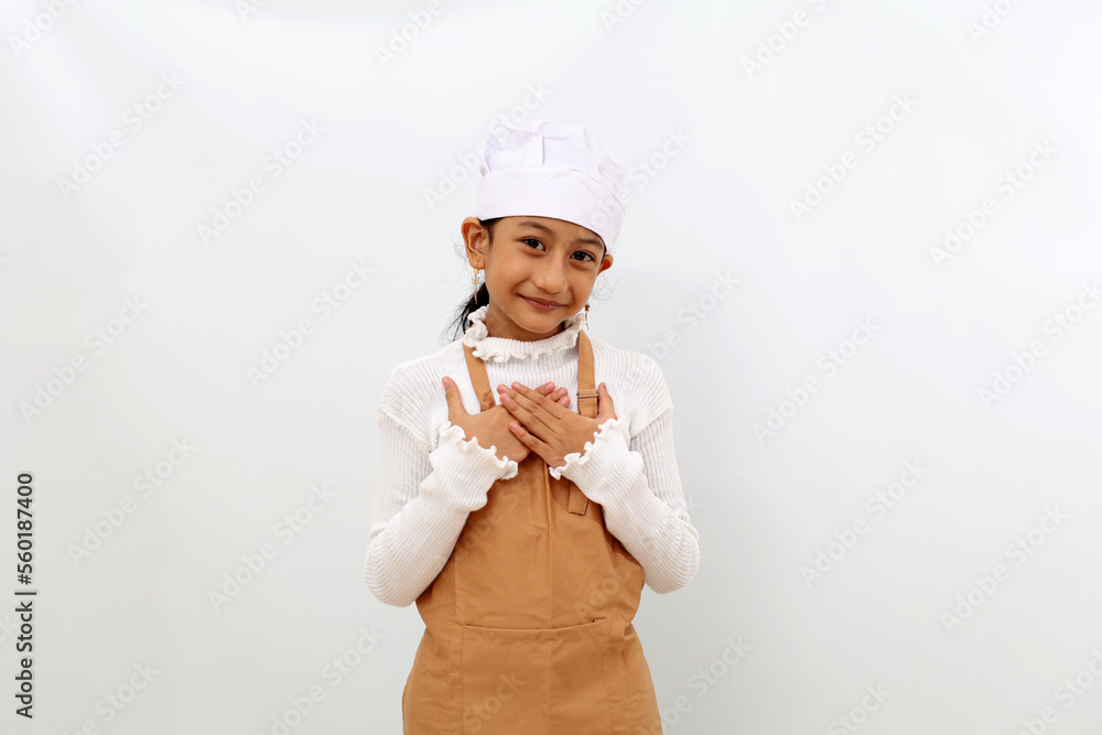 Relieved asian little girl in chef uniform standing while holding her ...
