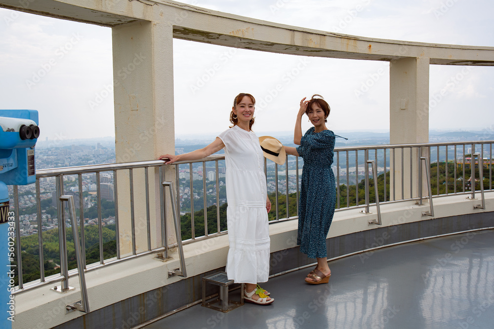 Two mature Japanese women at a viewing platform outdoors in summer ...