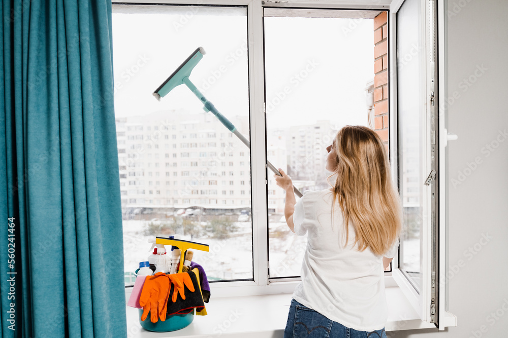 Woman cleaner with mop is cleaning window at home. Housekeeping ...