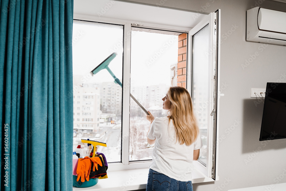 Housewife woman is cleaning at home and washing windows. House cleaning ...