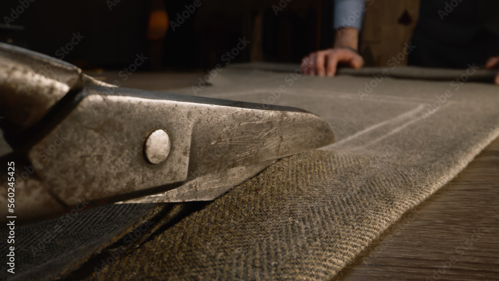 Close-up shot of tailor cutting fabric according to sketch using ...