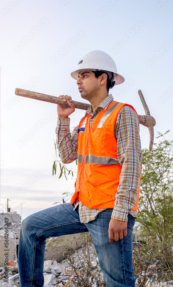 Worker with helmet and safety vest in profile. man with pickaxe in hand ...