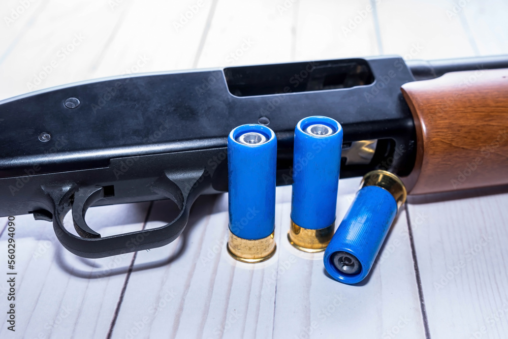 A 12 gauge shotgun with an opened chamber and three slug shells on ...