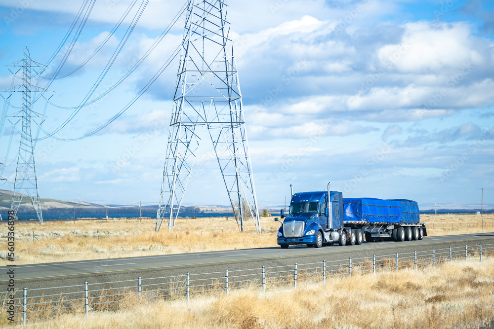 Blue big rig heavy duty semi truck with low profile cab transporting ...