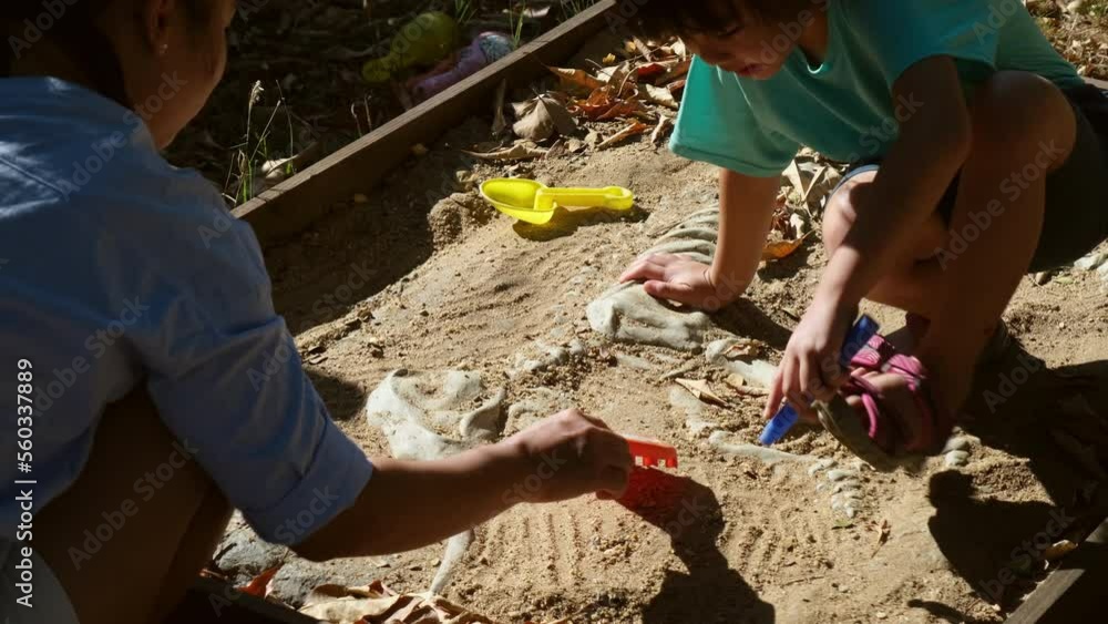 Cute little girl playing as a little archaeologist with her mother ...