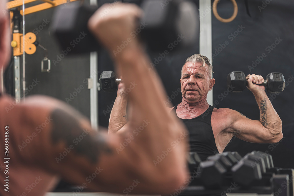 Foto de An old German man in his 60s doing seated dumbbell shoulder ...