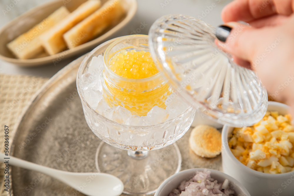 Gelber Saiblings Kaviar auf Eis in Glas Schale mit Porzellan Löffel ...