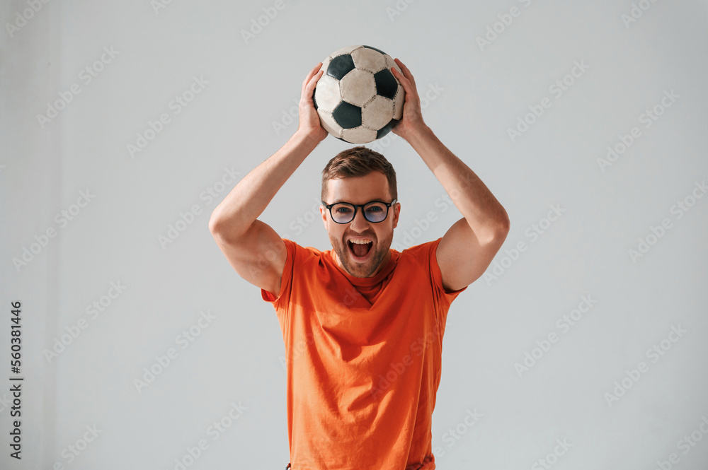 Active football fan is with soccer ball. Handsome man is in the studio ...