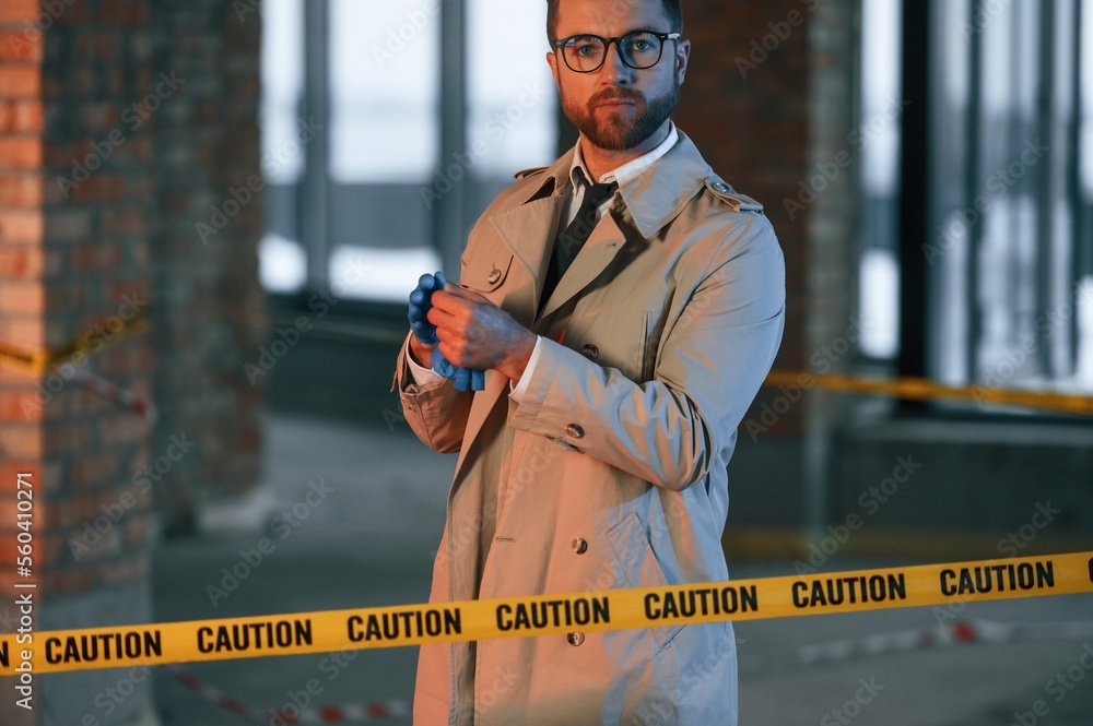 Taking off the gloves. Male detective in coat is collecting evidence in ...