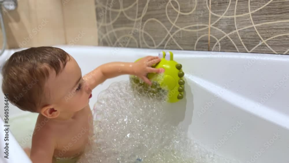 Caucasian toddler having a bath in the tub. Little boy touching the ...
