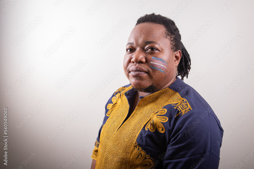 Studio portrait of a Trans African person with the trans flag drawn on ...