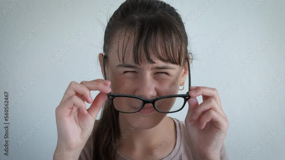 Girl puts on glasses with poor eyesight. An upset teen puts her glasses ...