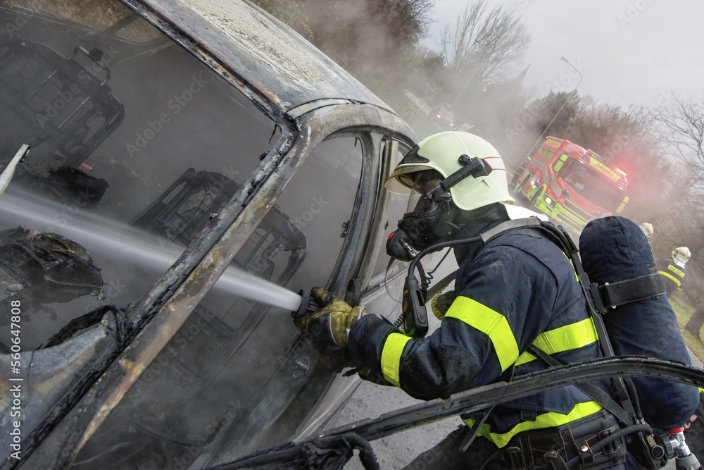 Firefighter with a breathing apparatus mask extinguishes a car fire ...