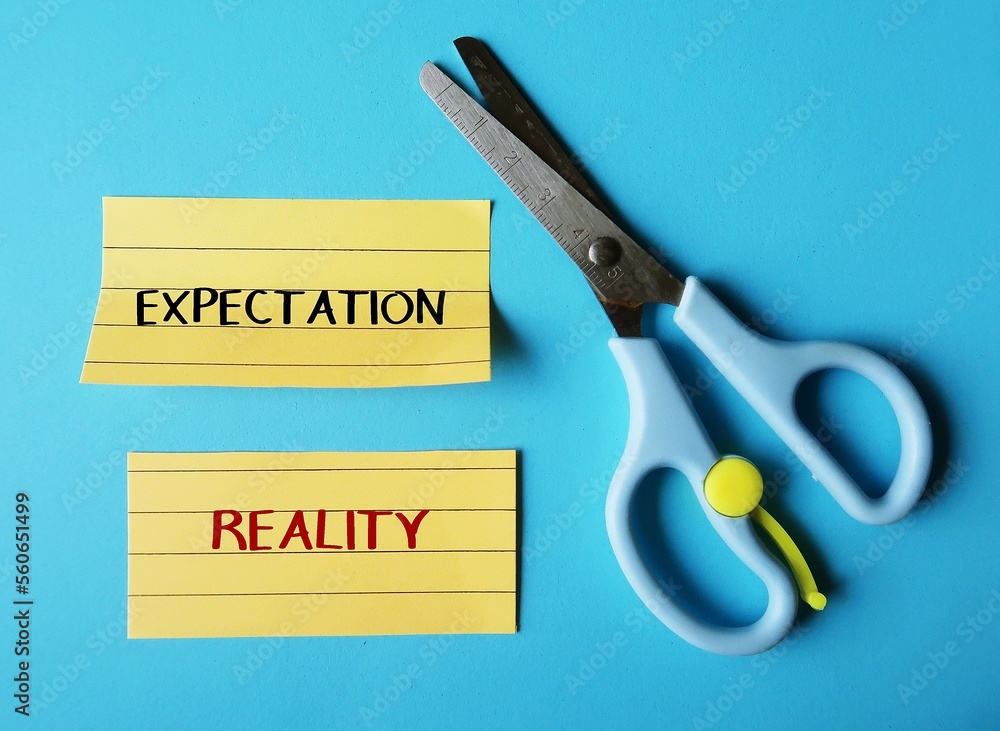Scissors cut two paper written EXPECTATION and REALITY, means ...
