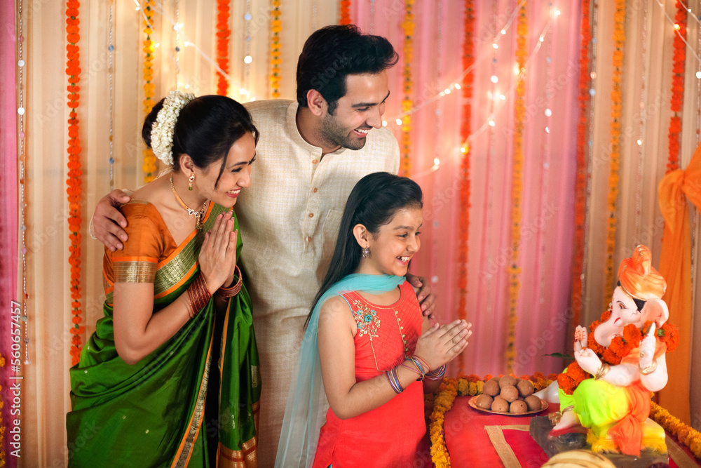 A happy Indian family in traditional dress performing puja / pooja at ...
