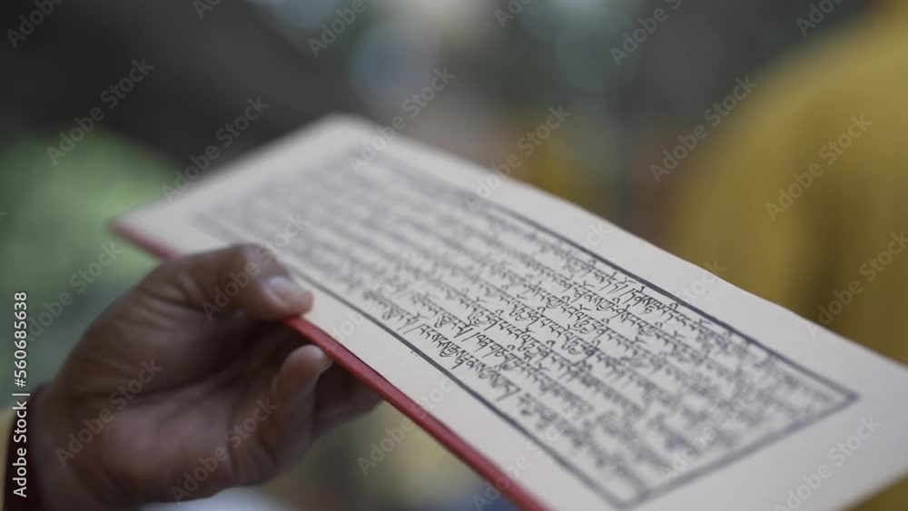 Hand holding a Sadhana text. Reciting buddhist prayers. Reading holy ...
