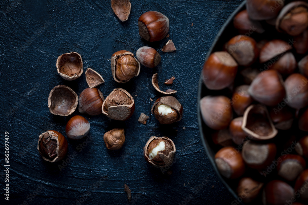 Cracked and unbroken shelled hazelnuts with a bowl of hazelnuts on a ...