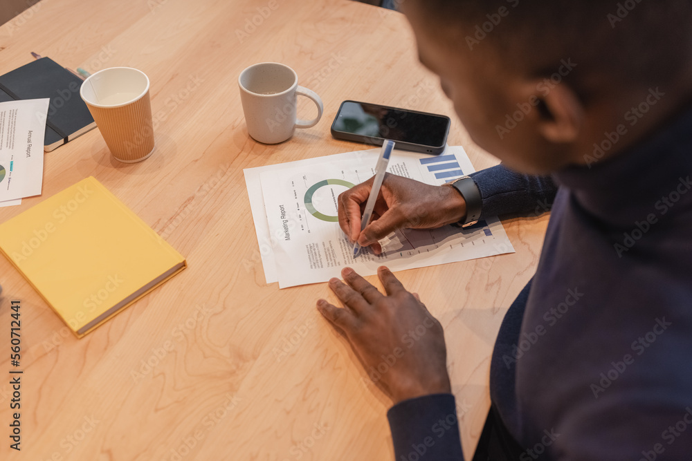 Black man making notes on graph paper Stock Photo | Adobe Stock