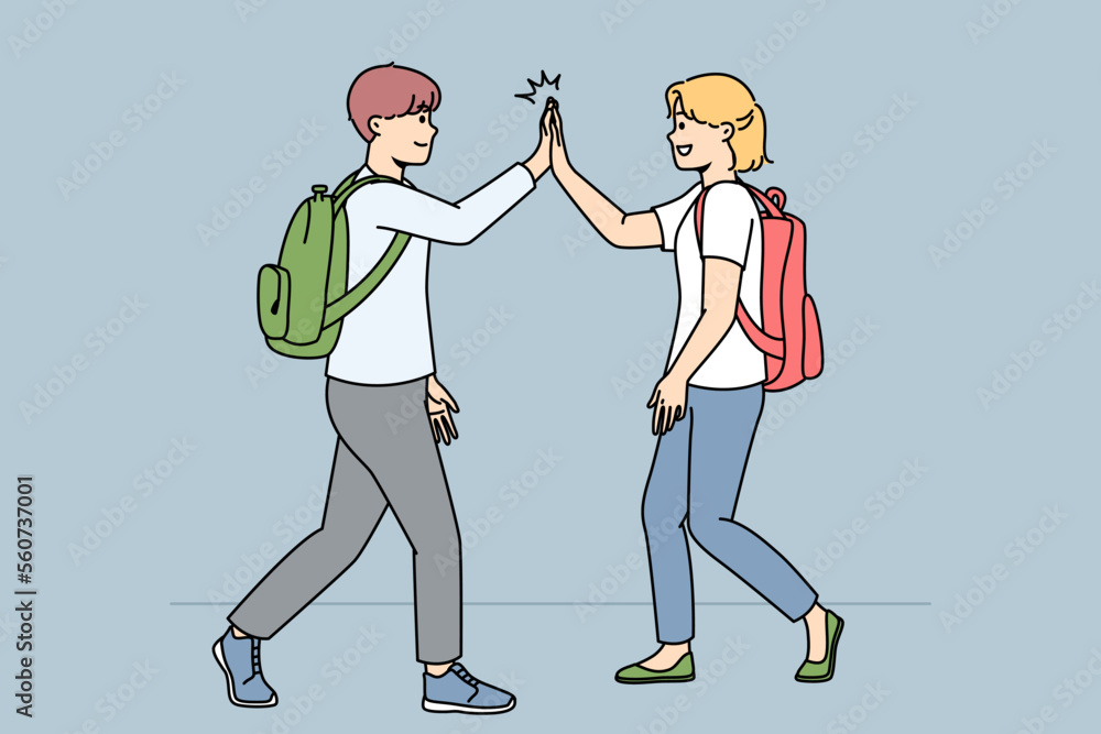 Smiling schoolchildren walking outdoors give high five. Happy friends ...