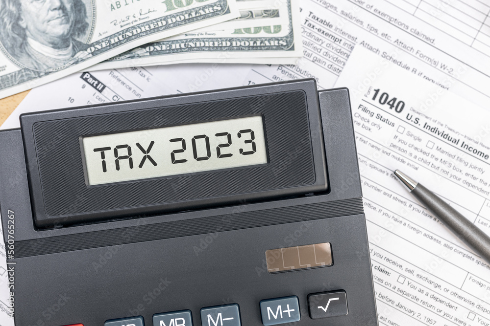 Tax time 2023 concept. Text on calculator screen, tex forms and dollar ...