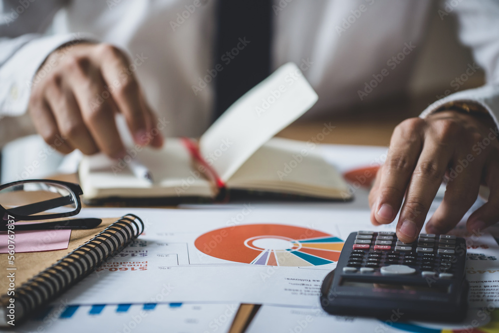 Man accountant use calculator and holding a pen and taking notes in a ...