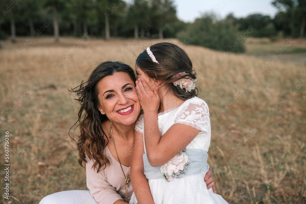 Communion girl tells a secret to her mother's ear Stock Photo | Adobe Stock