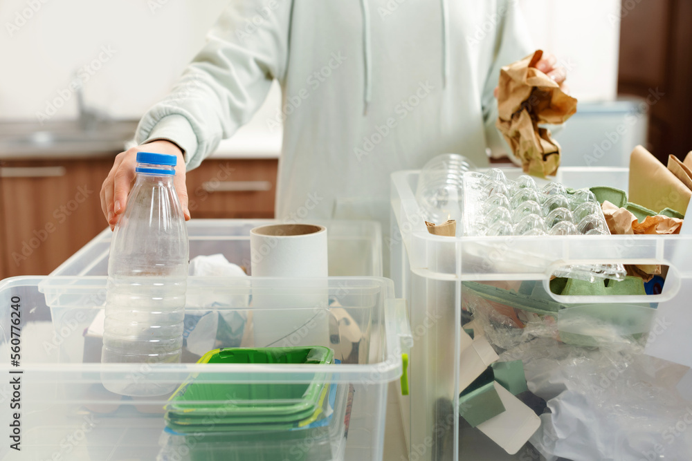 Female hands separate wastepaper and plastic garbage for recycling ...