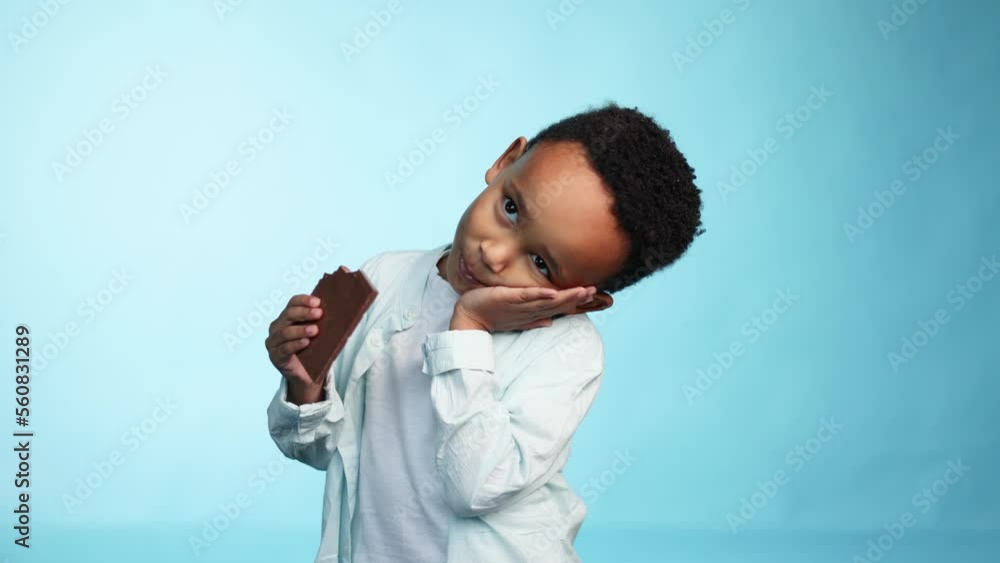 Cute little african american boy eating chocolate and having toothache ...