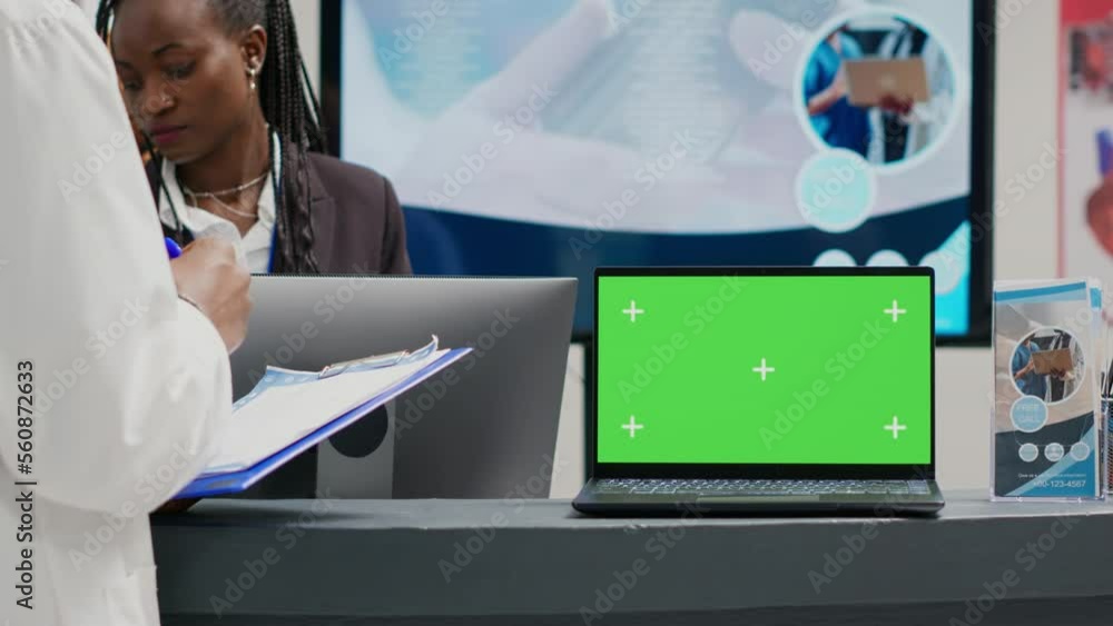 People working with greenscreen display on laptop in facility lobby ...