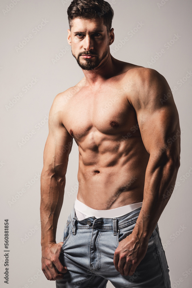 Male model with perfect body in jeans posing over grey background ...