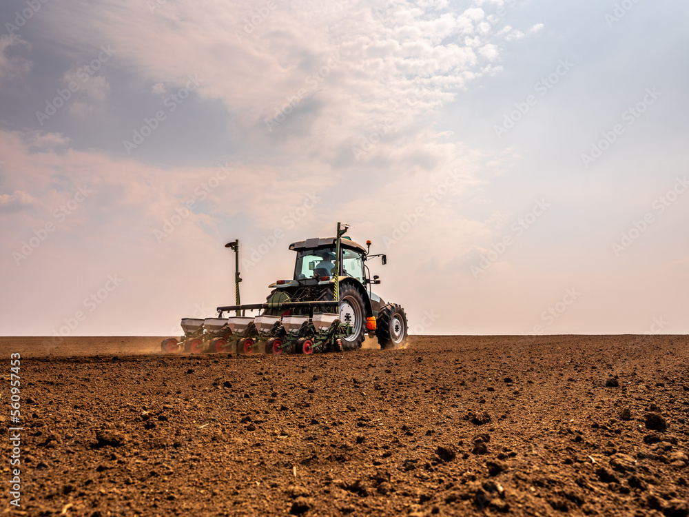 Agricultural worker planting soybean seeds with a tractor in a field ...