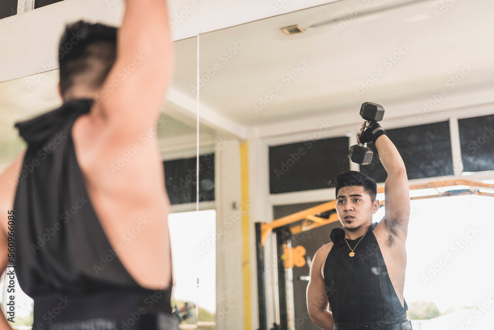 A fit asian man does a single arm overhead dumbbell tricep extension ...
