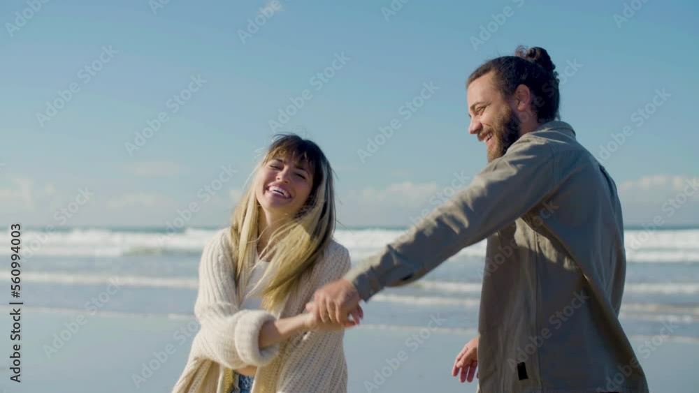 Romantic Caucasian couple having fun at seashore while waves rushing in background. Happy ...