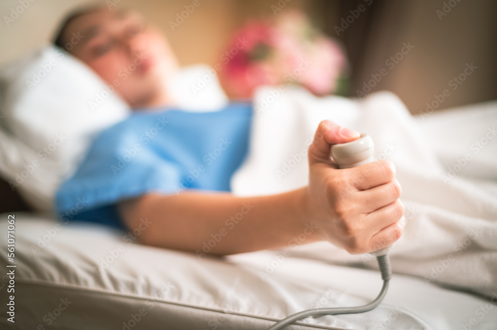 Patient in a hospital room calling a nurse. A hand holding press ...