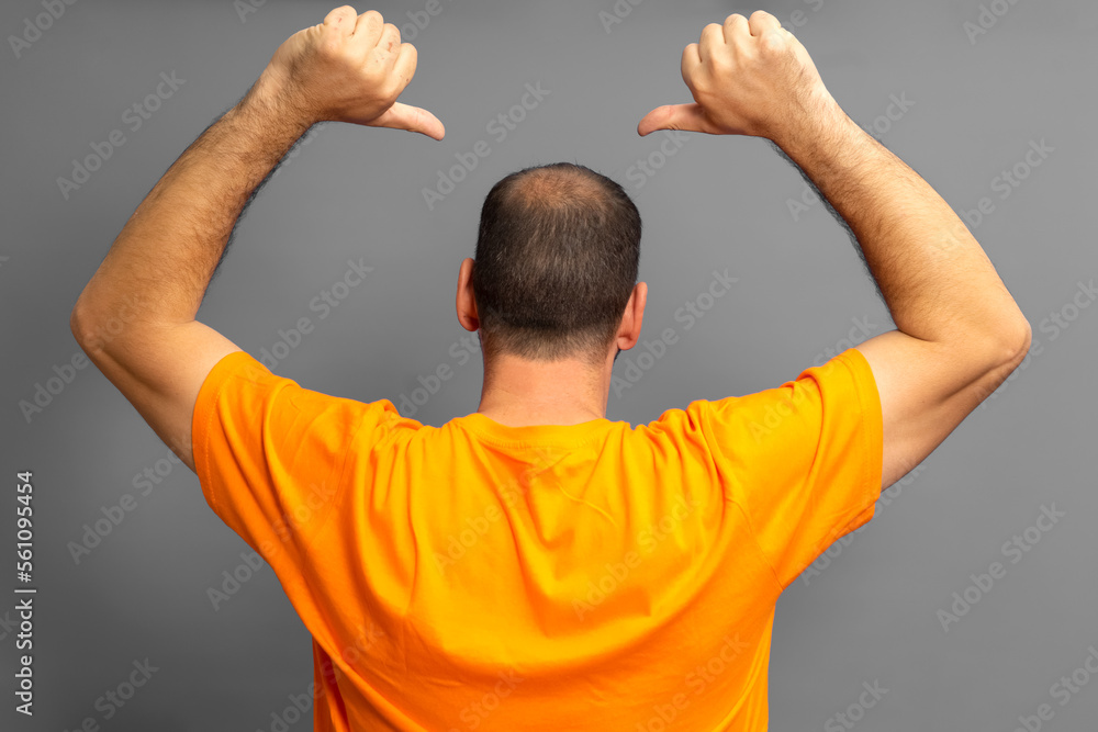 Proud man in orange t-shirt with his back turned pointing with his ...