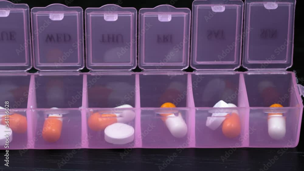 Woman's hand puts pills for week in pill dispenser. Concept of health ...