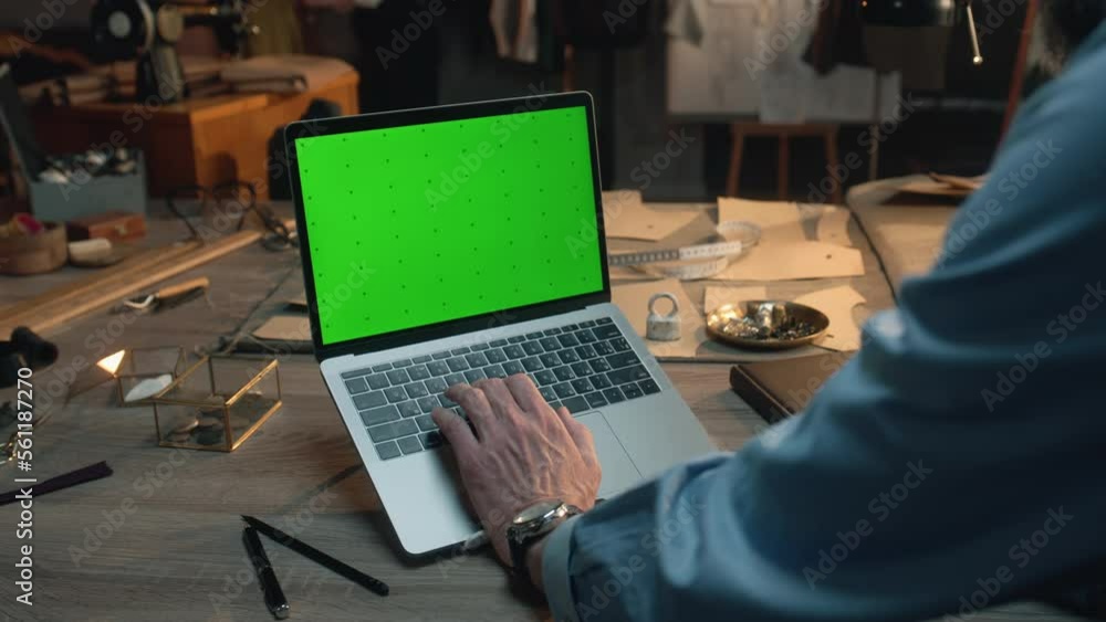 Successful businessman sits on workplace in luxury atelier and types on ...