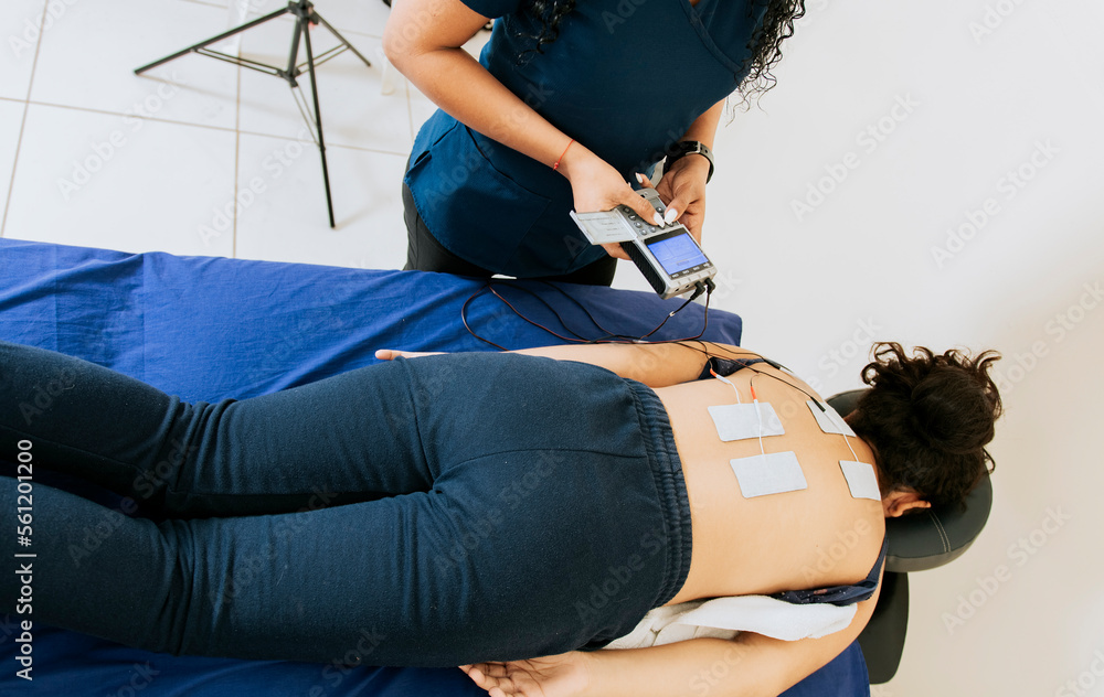 Professional physiotherapist electrostimulating a lying patient ...