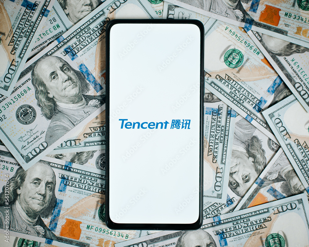 Tencent Chinese company logo on screen of mobile phone lying on pile of ...