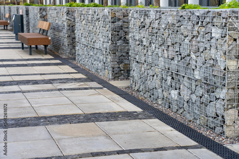 Perspective view of paved walkway with modern wooden bench in front of ...