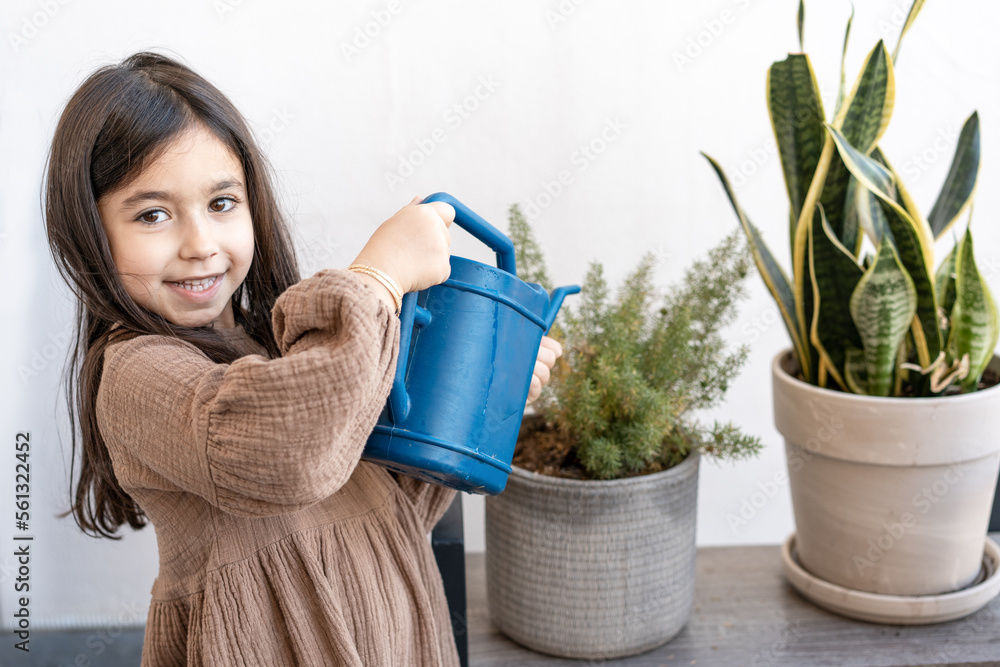 Little girl is watering plants with water can on roof terrace. Active ...