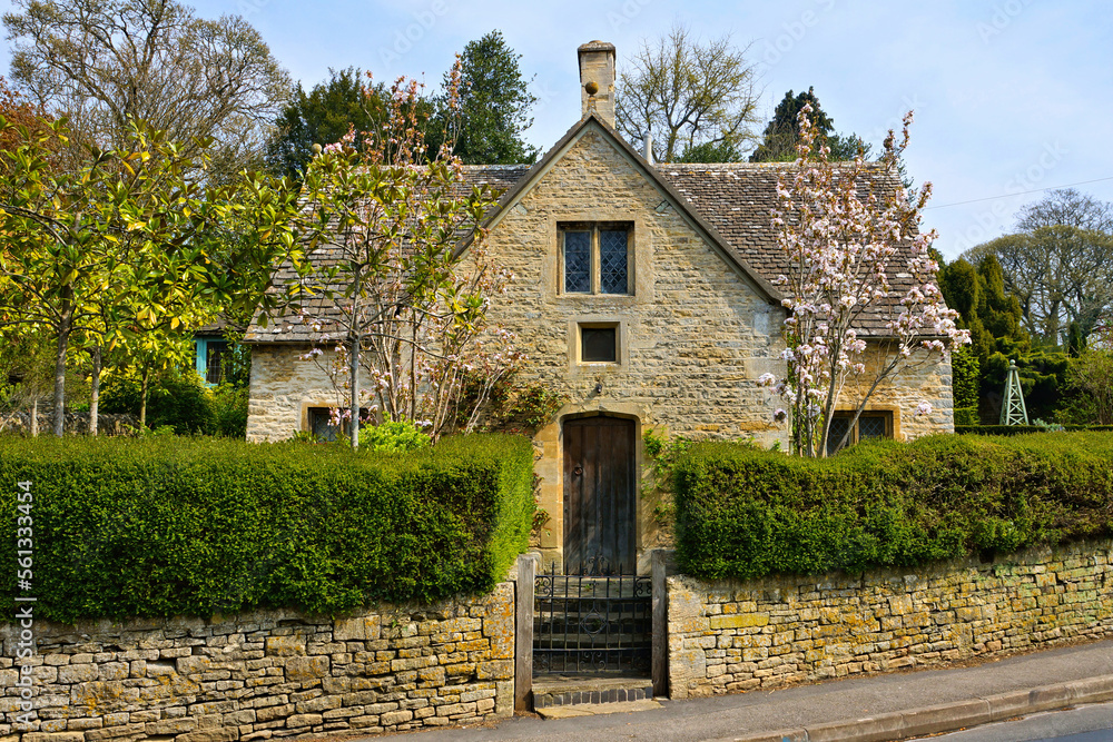 Quaint stone house in the Cotwolds of England with hedge and flowering ...