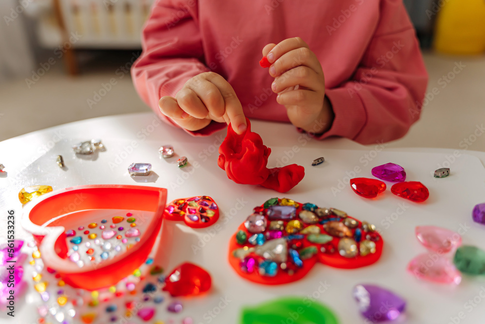 Child hands creating red heart from play dough for modeling with ...