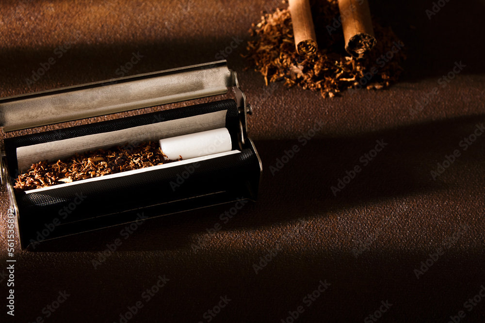 Hand-rolled cigarette, rolling machine, cigarillos, scattered tobacco ...