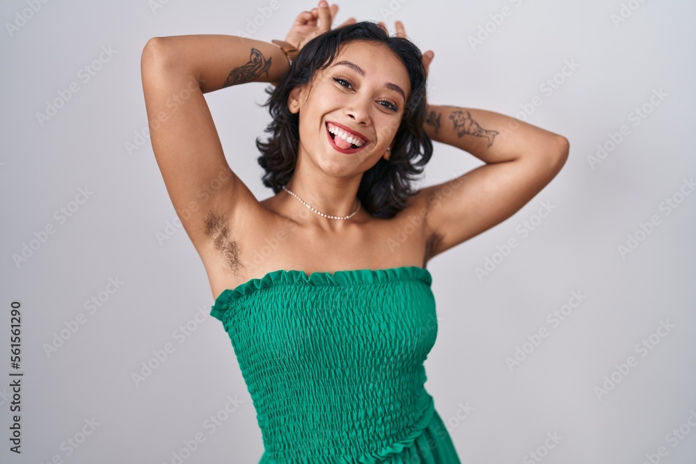 Young hispanic woman standing over isolated background posing funny and ...