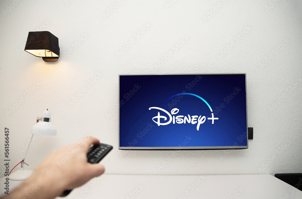 Una tele de hotel con el logo de Disney + y un mano de hombre sujetando ...